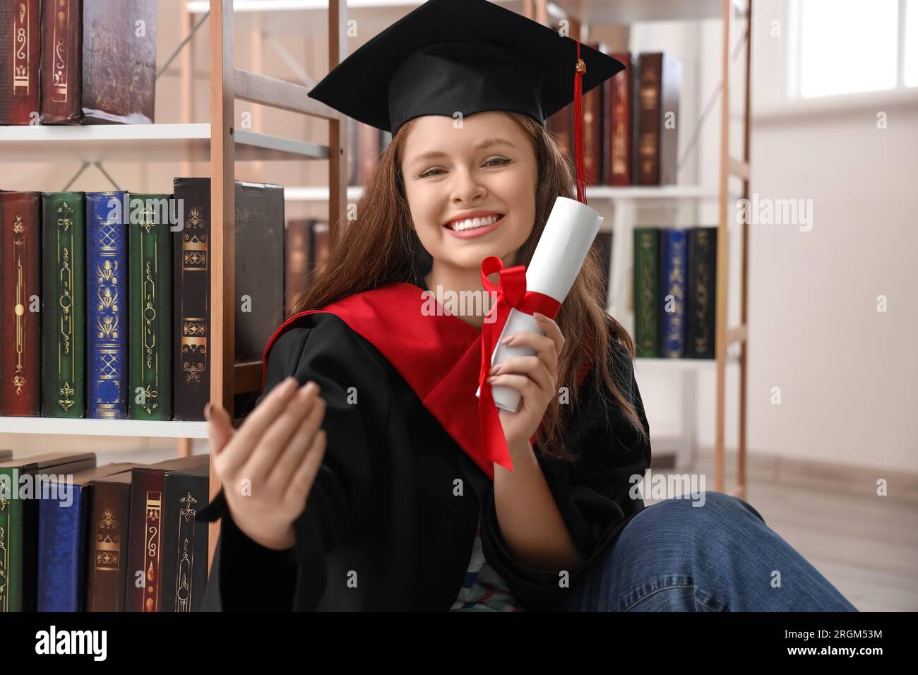 Female graduate student with diploma in library Stock Photo - Alamy