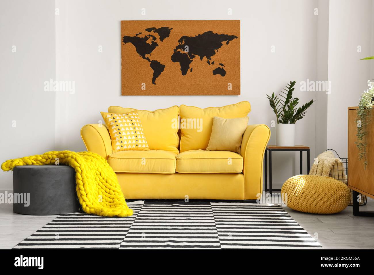Interior of stylish living room with cozy yellow sofa and soft knitted blanket on pouf Stock ...