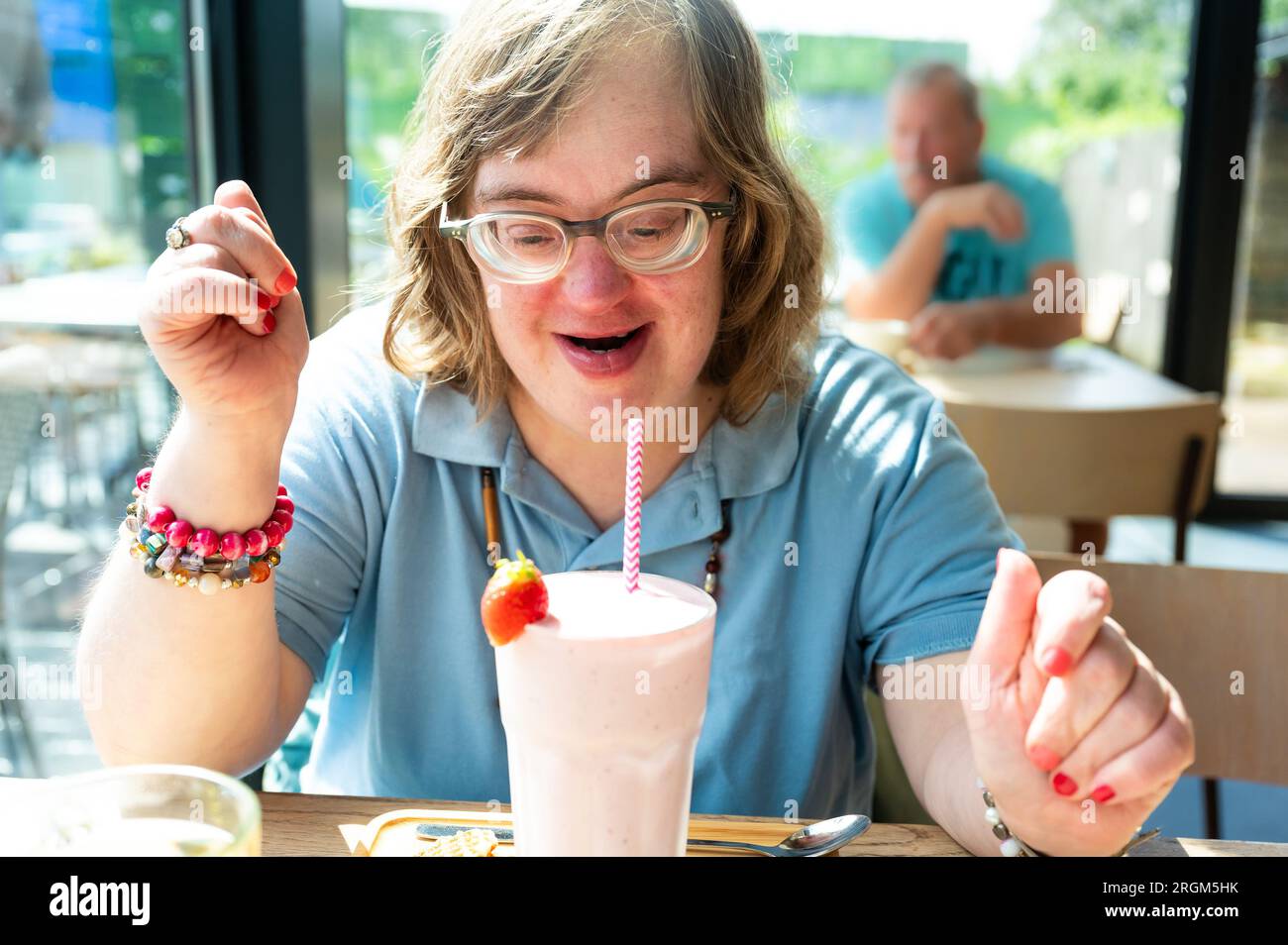 Portrait of a 40 yo woman with the Down Syndrome drinking a strawberry ...