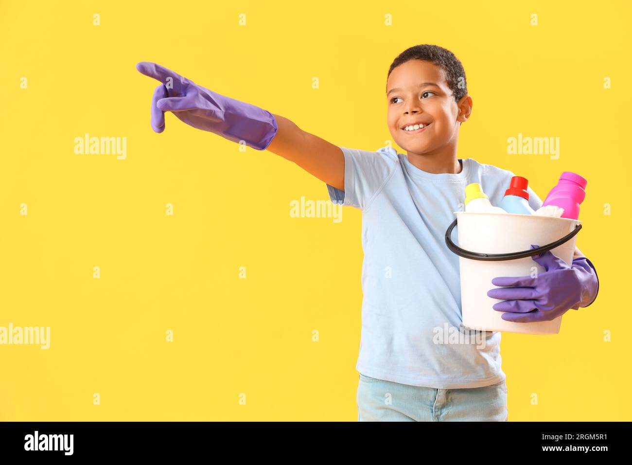 Little African-American boy with cleaning supplies in bucket pointing ...