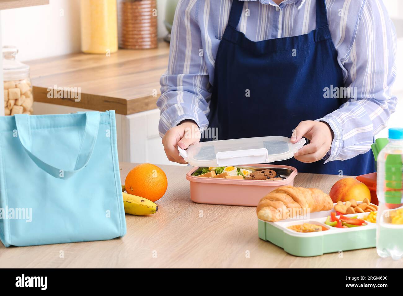 Mother packing meal in lunchbox for school on table at kitchen Stock ...