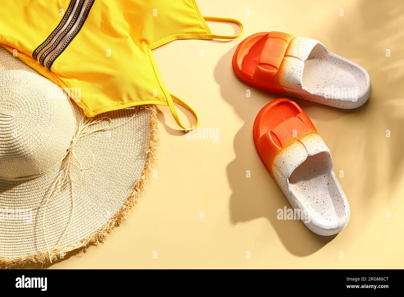 Female stylish flip flops with beach accessories on pale yellow ...