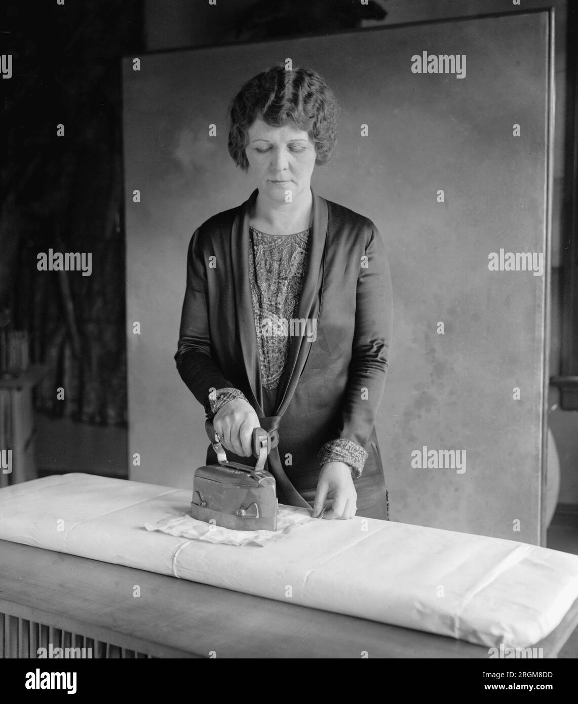 Woman demonstrating how to use an iron ca. 1925 Stock Photo - Alamy