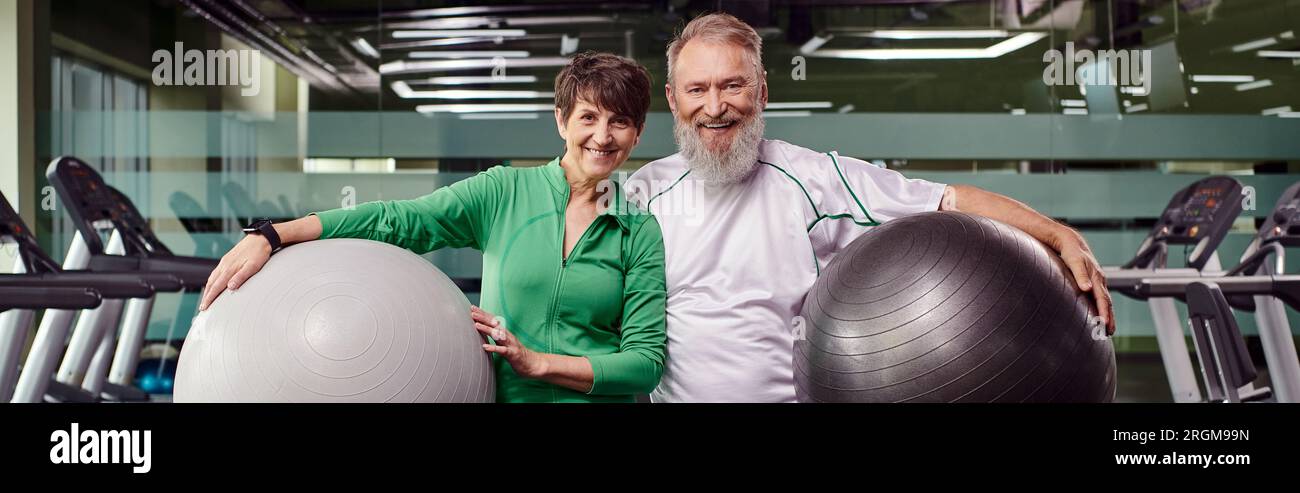 sporty elderly couple, happy man and woman holding fitness balls ...