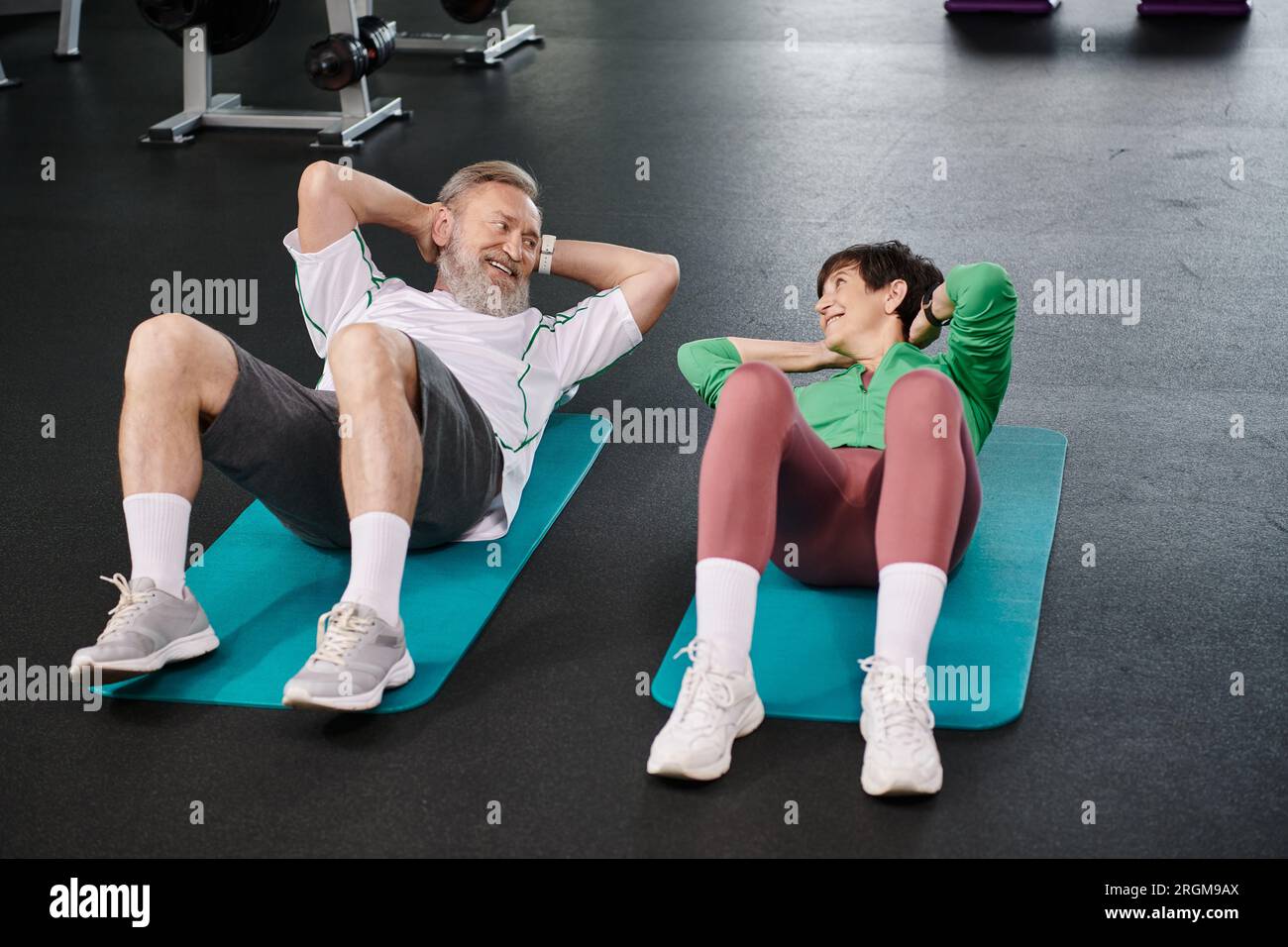 elderly man and woman doing sit ups, active seniors exercising on ...