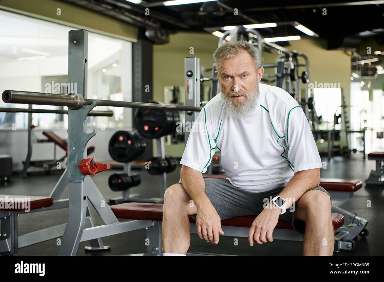 tired elderly man with beard looking at camera after workout, exercise ...