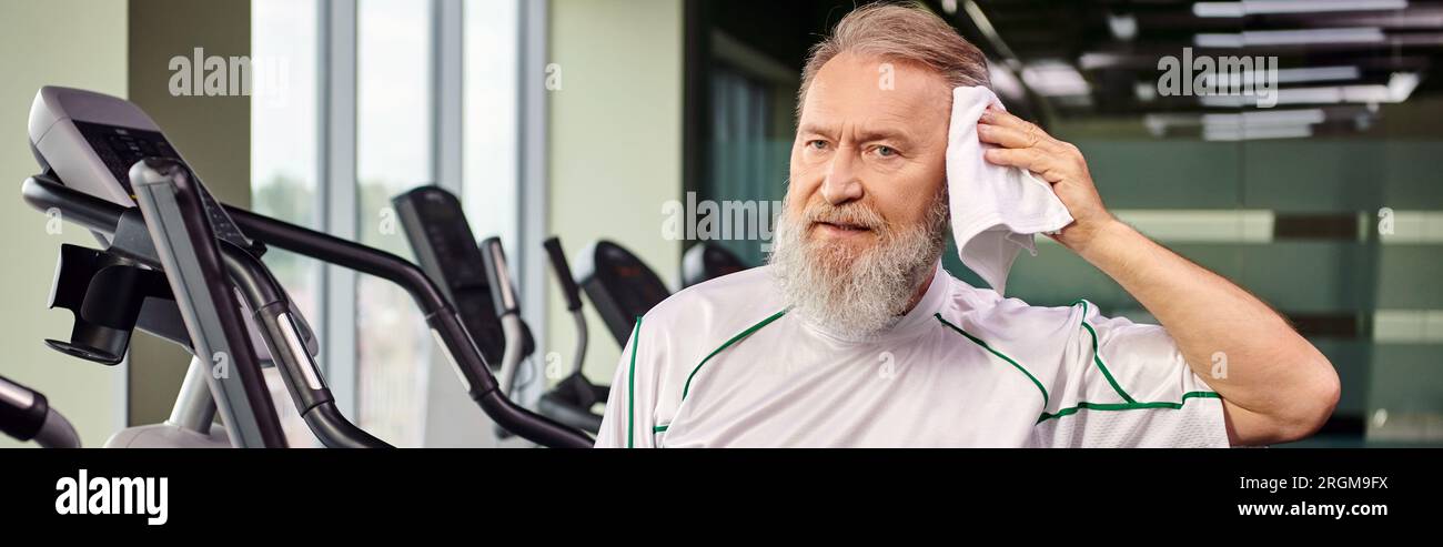 horizontal, banner, senior man with beard wiping sweat with towel after ...