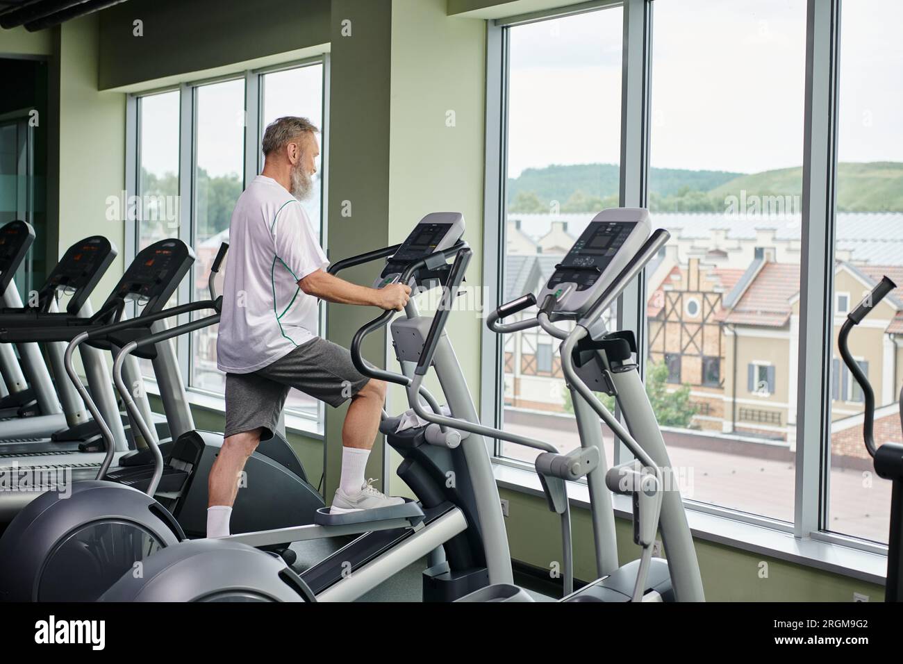 bearded man working out on stepper machine, elderly in gym, active ...