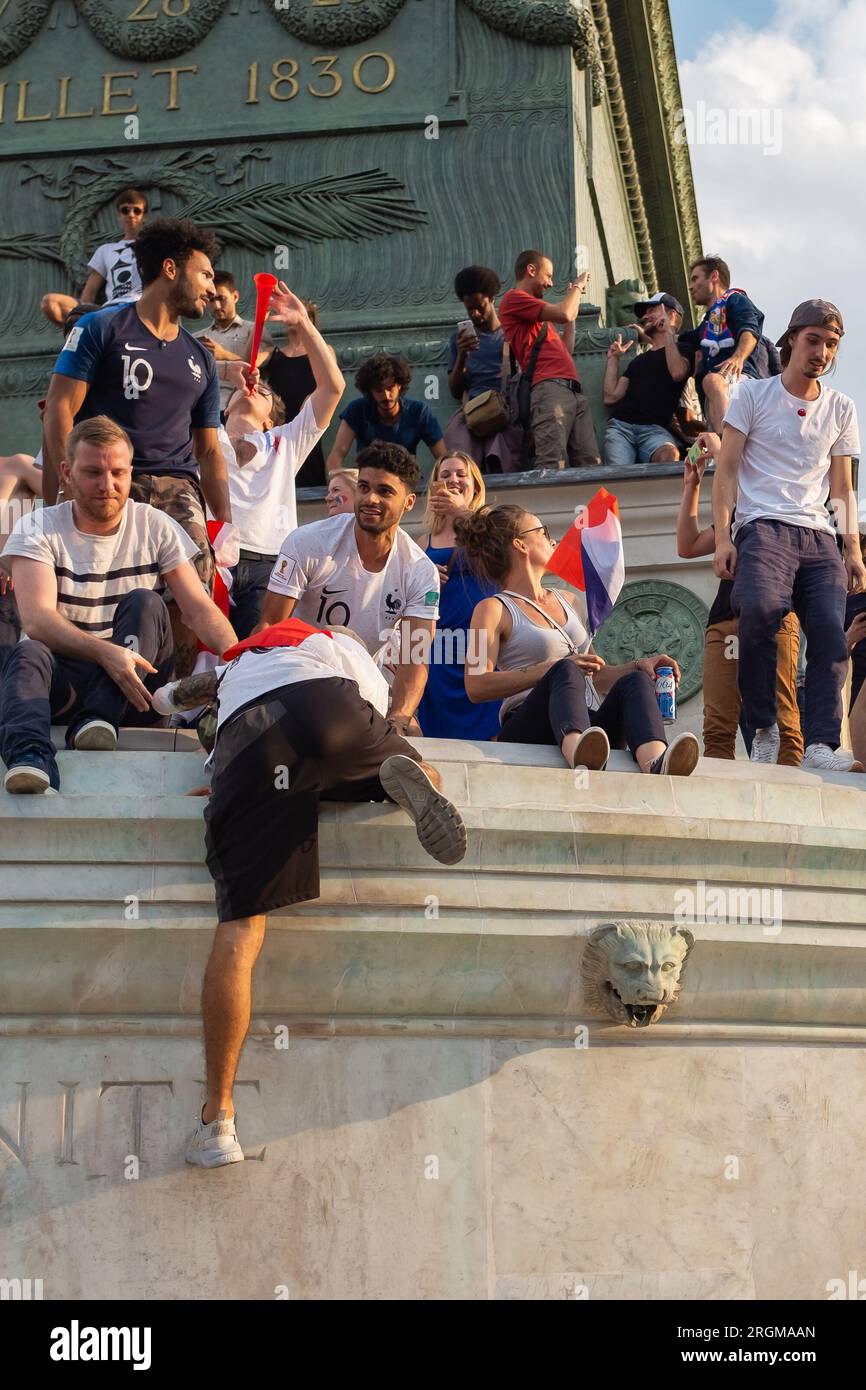 Paris, France, 2018. A man climbing the July Column with a flag wrapped ...