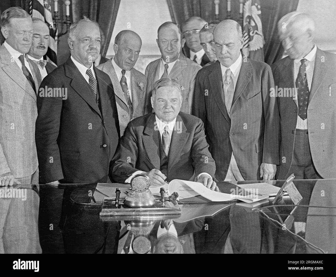 President Herbert Hoover signing a bill into law, surrounded by fellow ...
