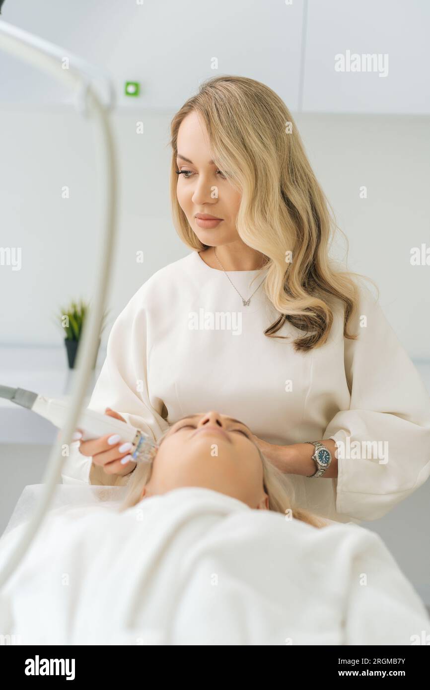 Vertical shot of female doctor performing non-invasive RF facial ...