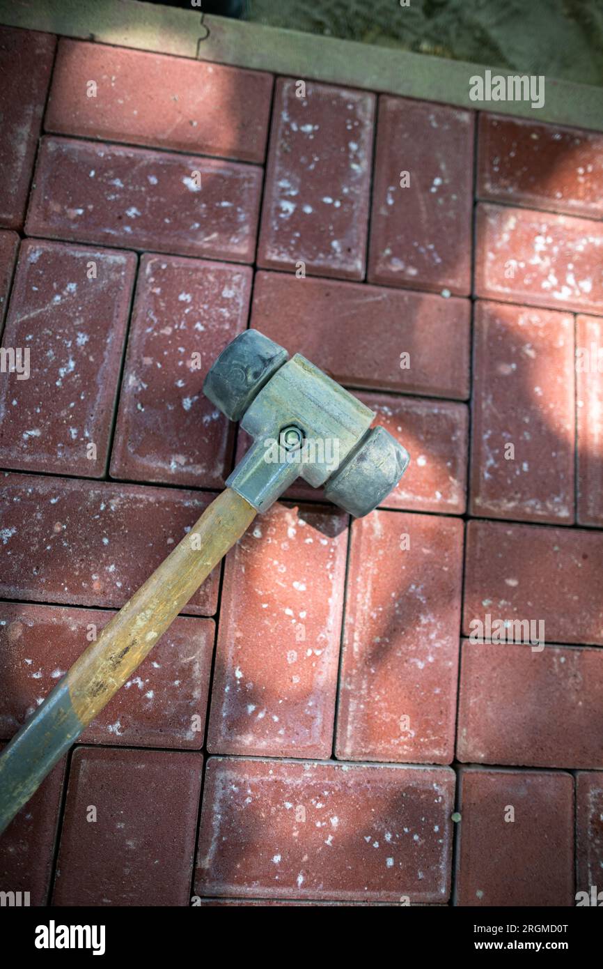 A hammer with rubber tips used in paving works lies on the paving ...