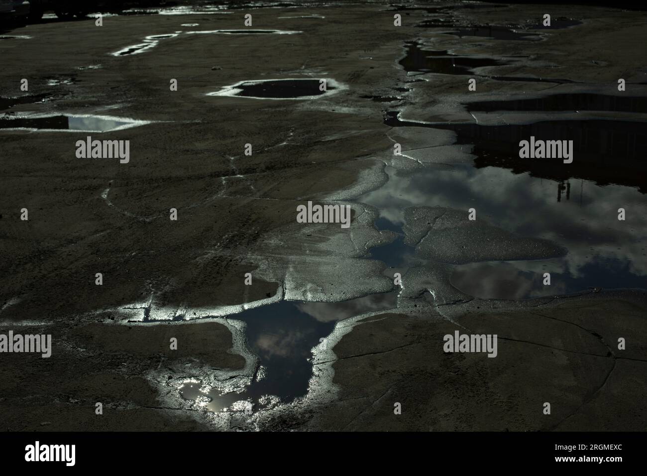 Puddle on pavement. After rain. Road in pits. Reflection of sky in ...