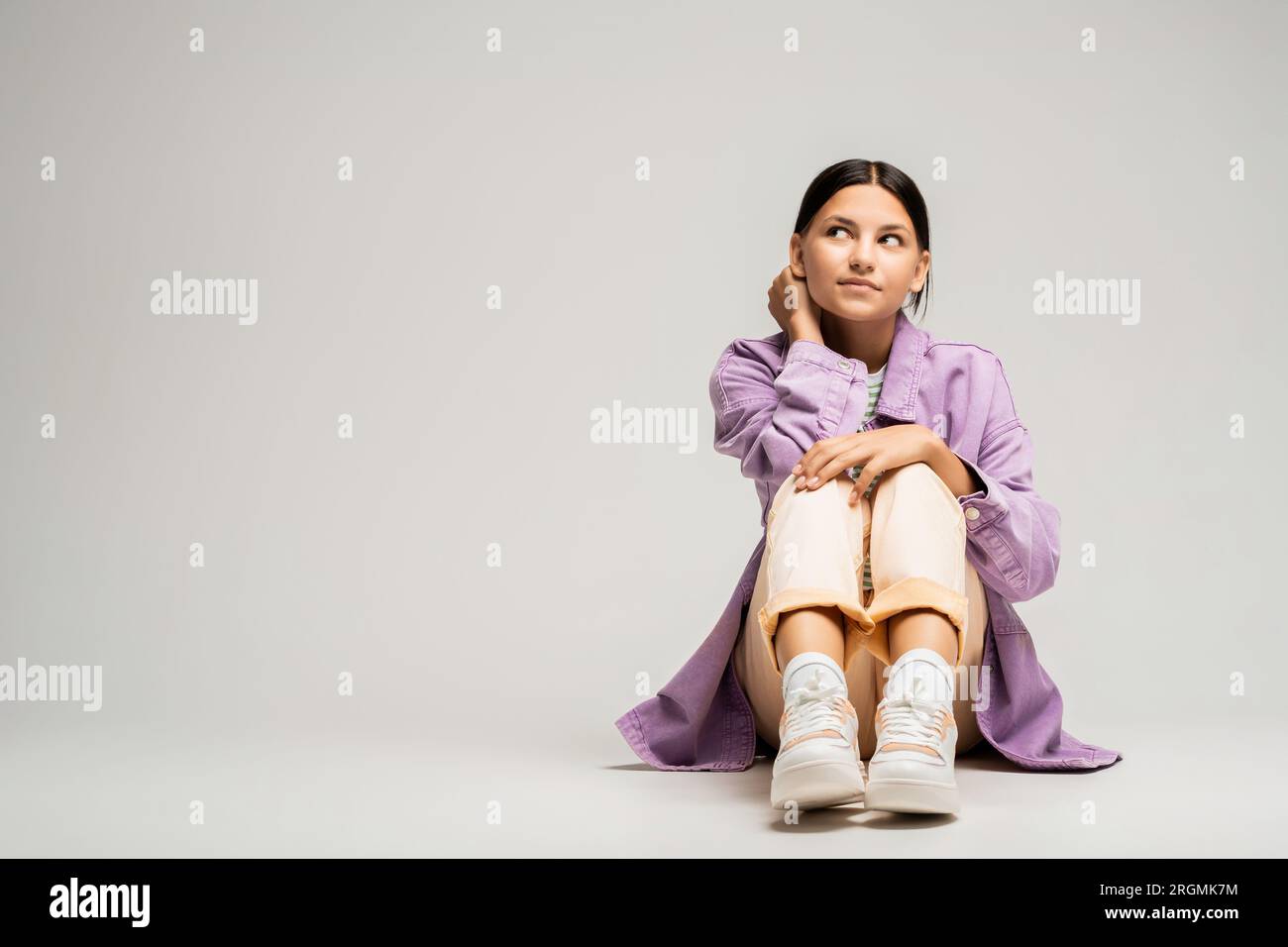 Teenage sits on floor with legs tucked up to chest. Dreamy girl full of ...