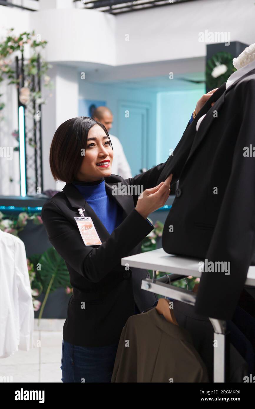 Retail center boutique asian woman employee adjusting jacket on ...