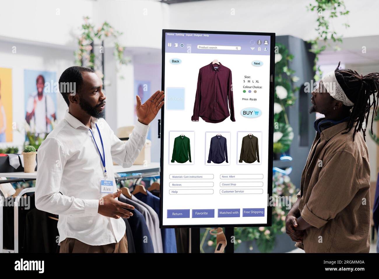 Male assistant showing clothes on interactive kiosk board to young ...