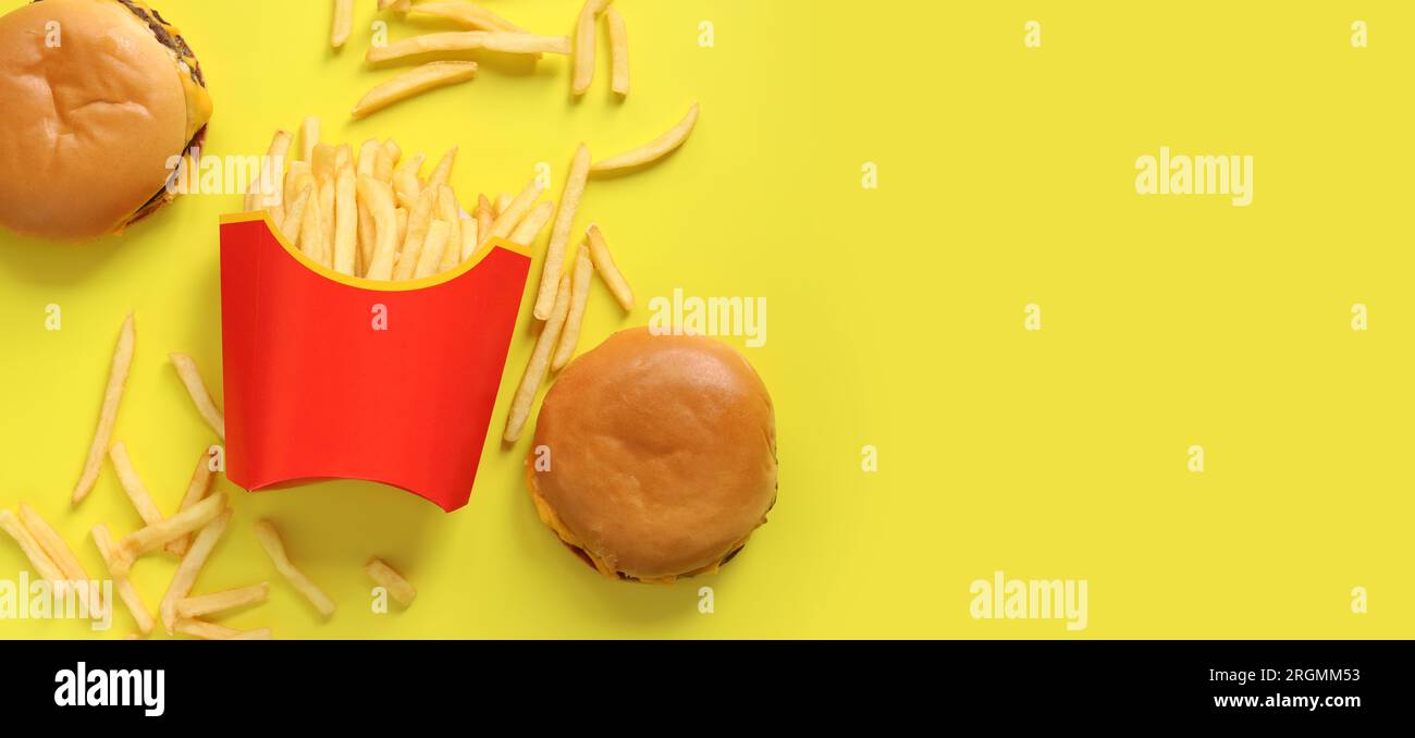French fries in paper packaging and burgers on a yellow background, top ...