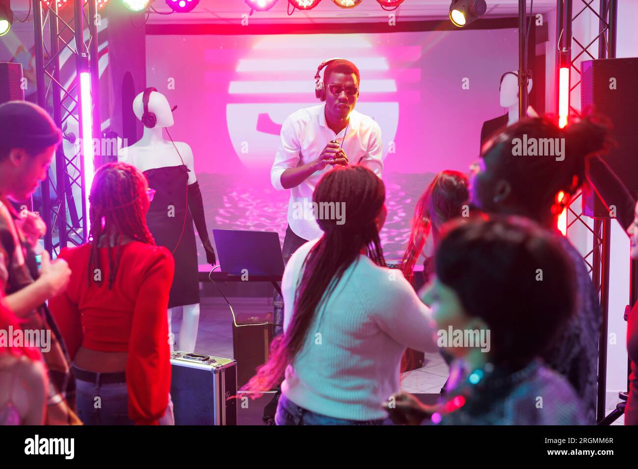 Dj mixing music and singing in microphone while crowd dancing and ...