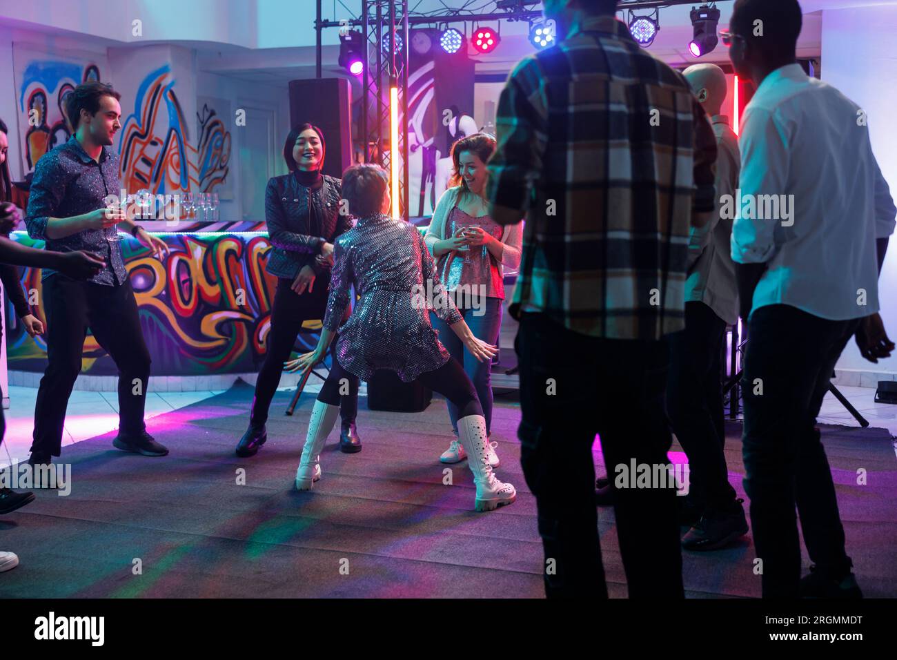 Friends enjoying night out in club while dancing and laughing together ...