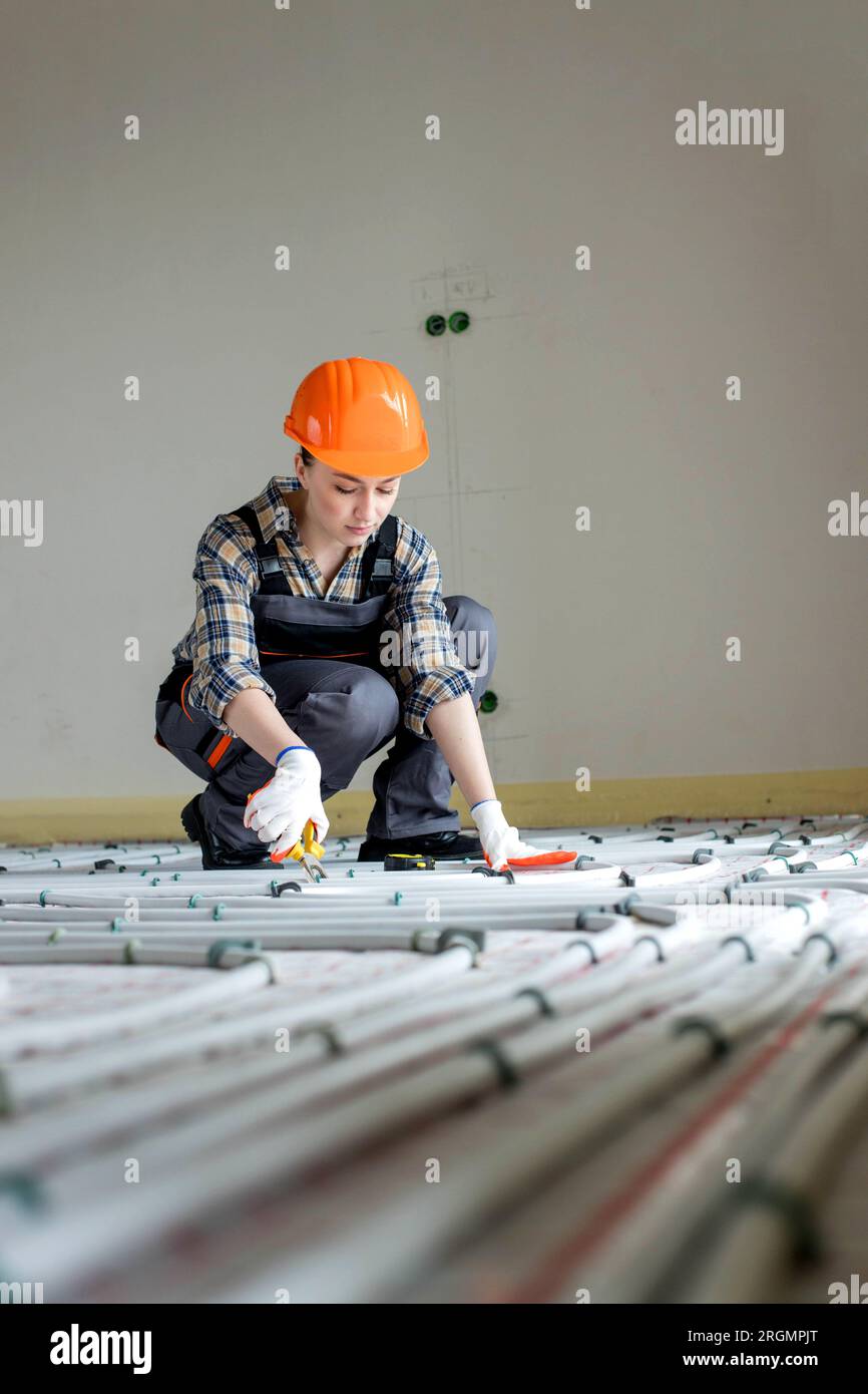 Woman worker is installing underfloor heating system. Warm floor ...