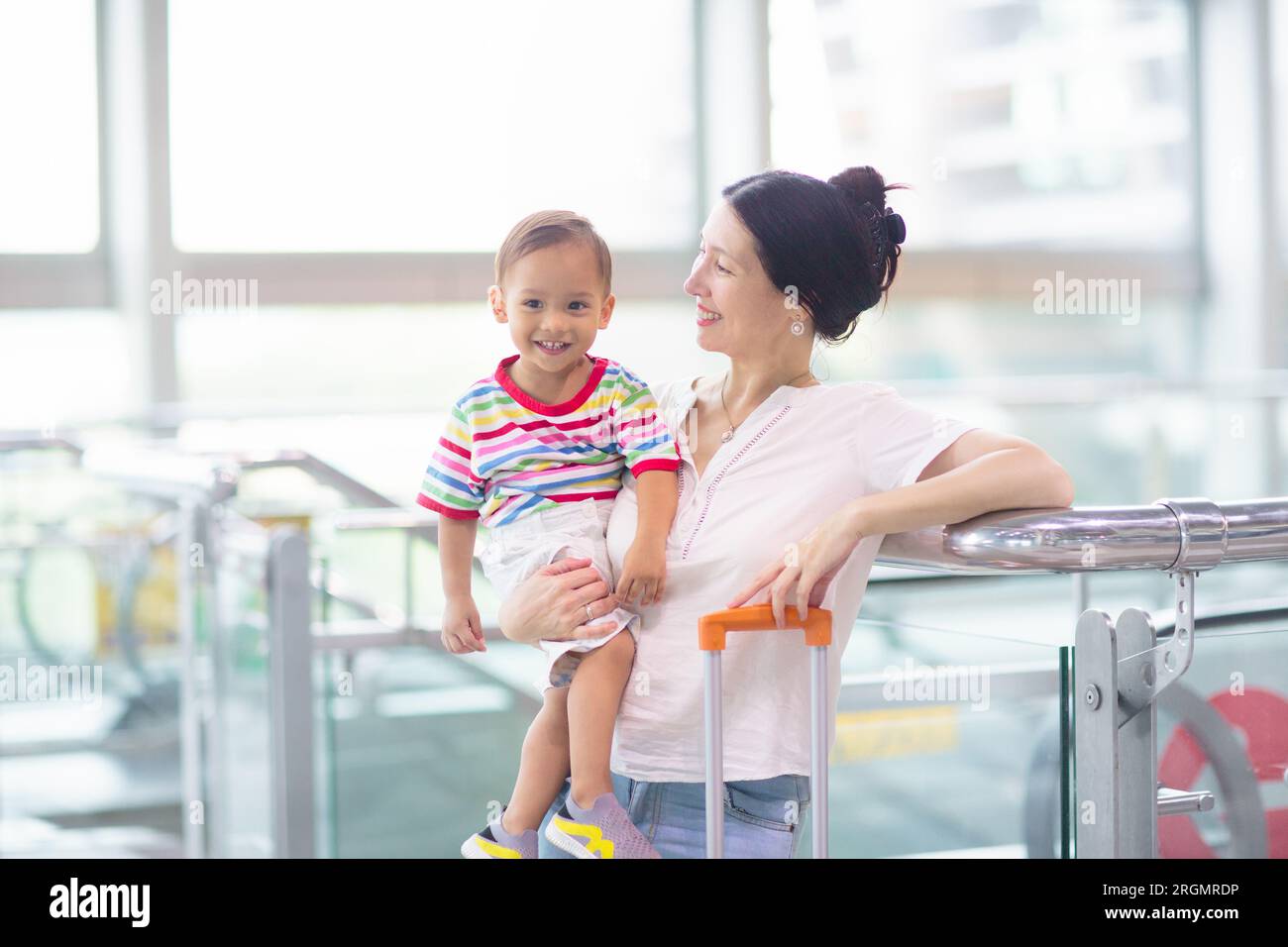 Family in airport. Young Asian mother and child travel by air. Fly with ...