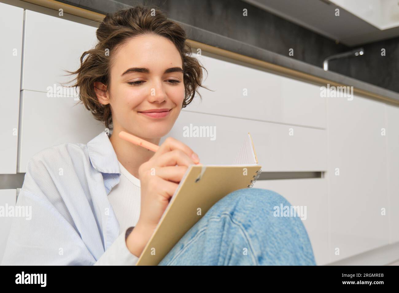 Hobbies and lifestyle concept. Happy young woman sits on floor with pen ...