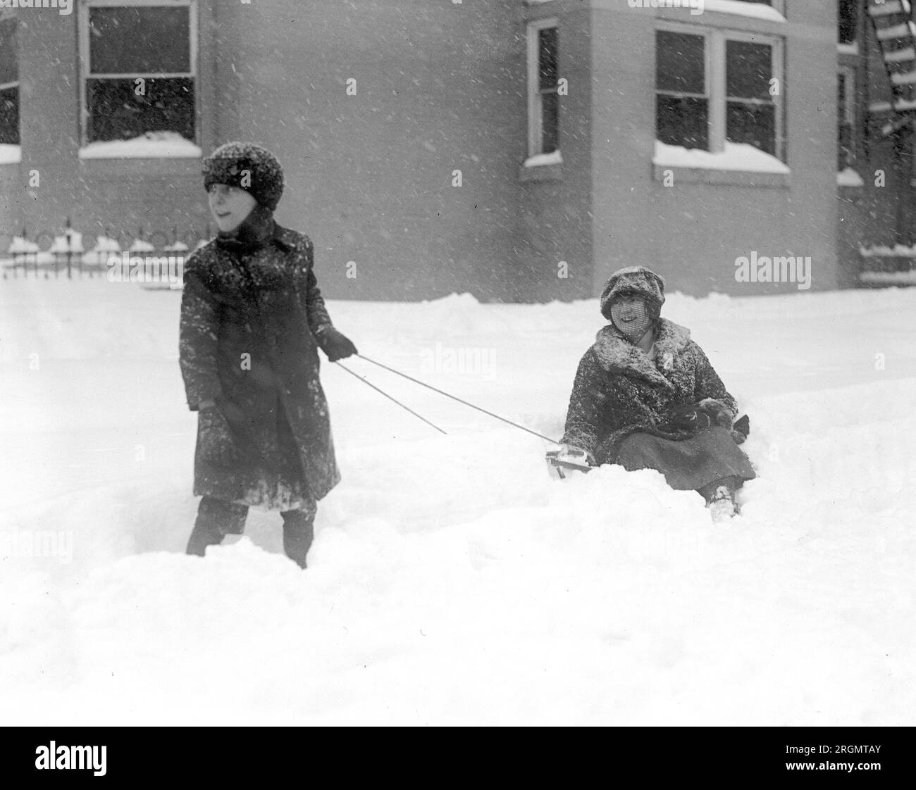A child playing in the snow with his mother during or after a blizzard ...