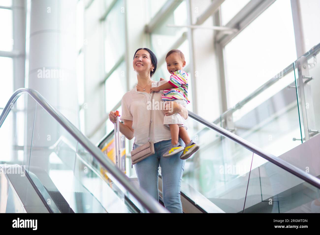 Family in airport. Young Asian mother and child travel by air. Fly with ...