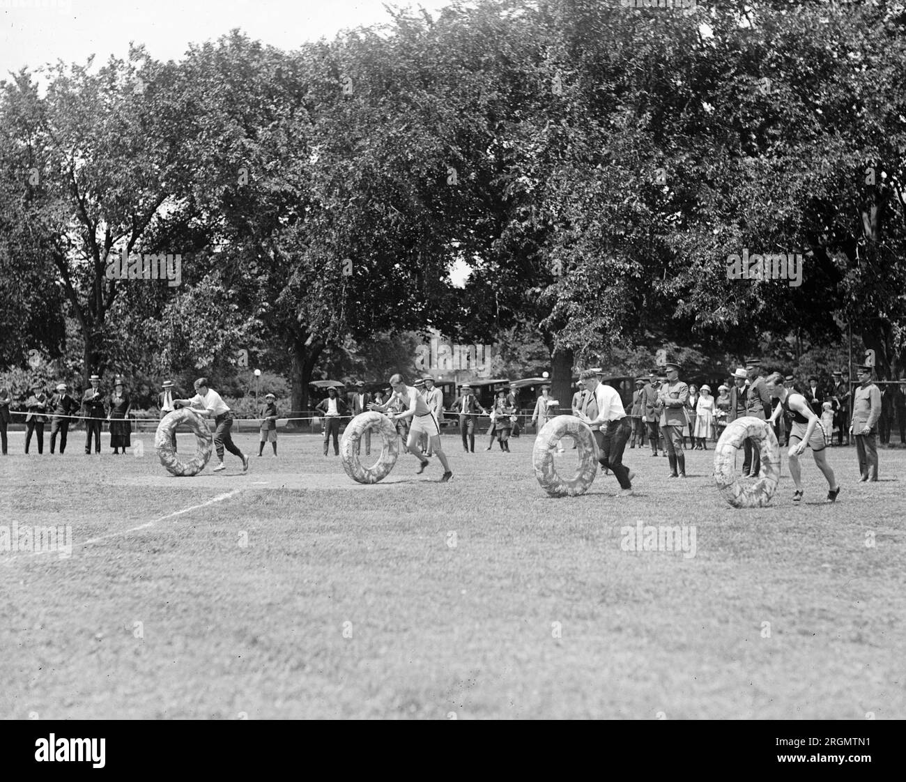Men participating in a doughnut race (donut rolling race) ca. 1922 ...