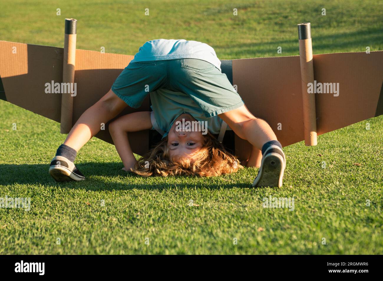 Funny child upside down on grass. Childhood imagination. Kid dreams of future. Kid pilot ...