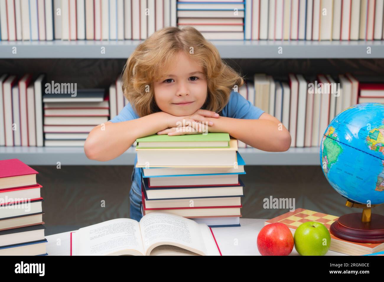 School boy with stack of books in library. School child. Kid boy from ...