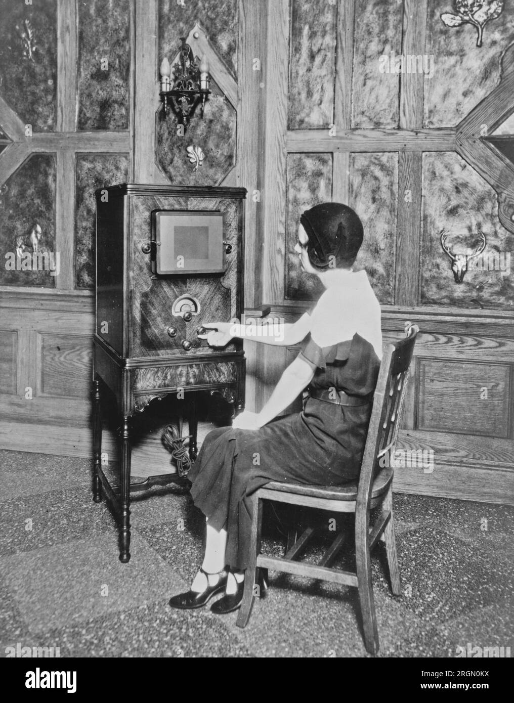 Woman, full-length, seated, facing left, turning dial of a console ...