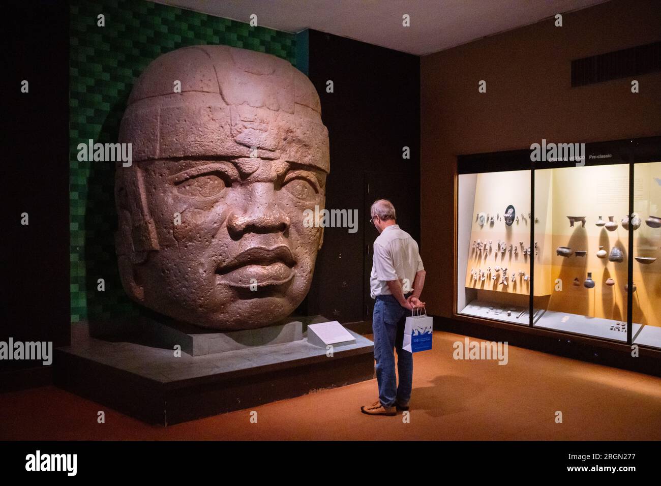 Man watching Olmec head replica of a sculpture that was discovered in ...