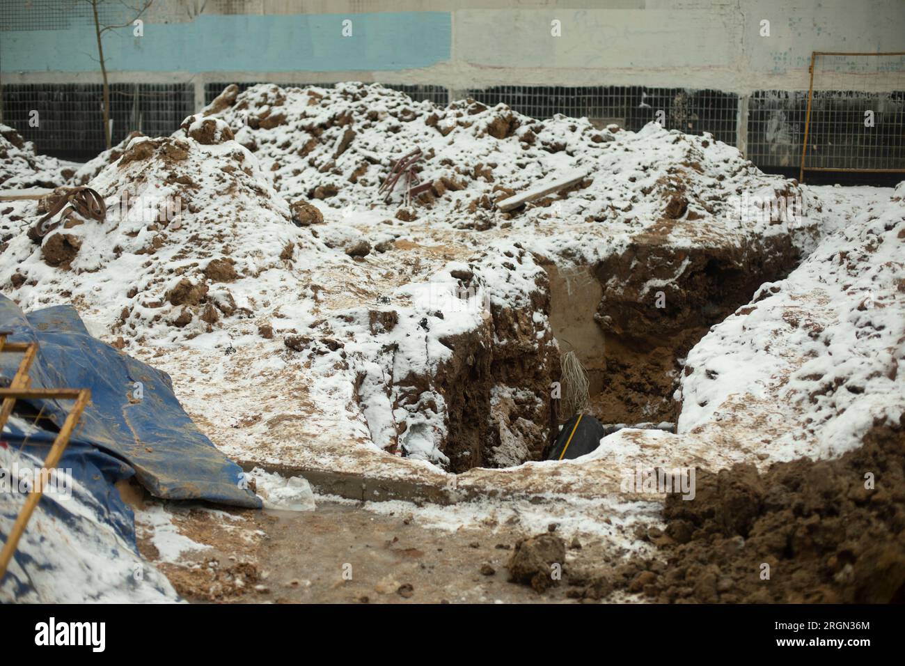 Pit for laying heating pipes in winter. Dug frozen ground in yard ...