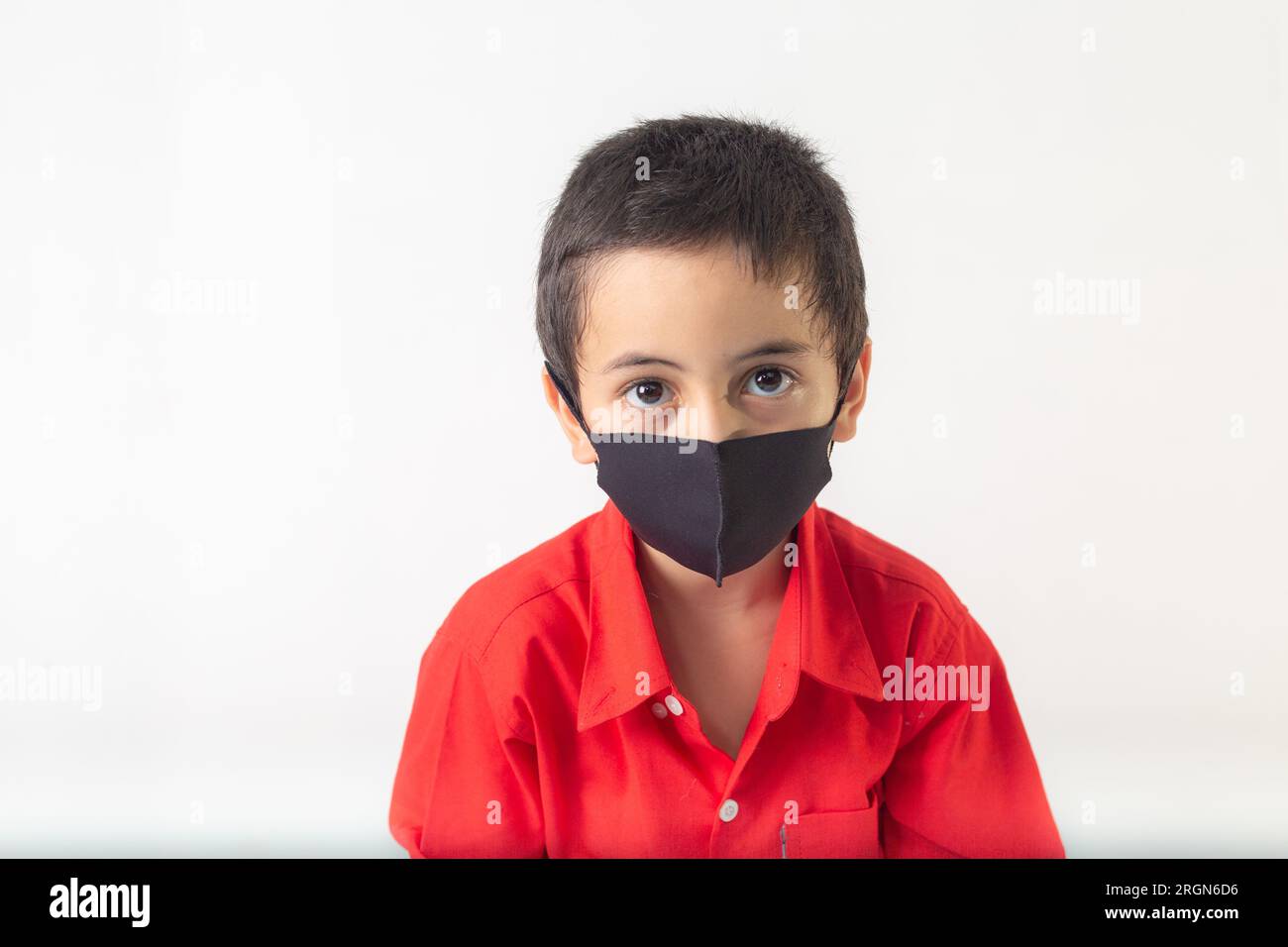 Cute boy in red shirt wearing black mask Cheerful appearance sitting in ...
