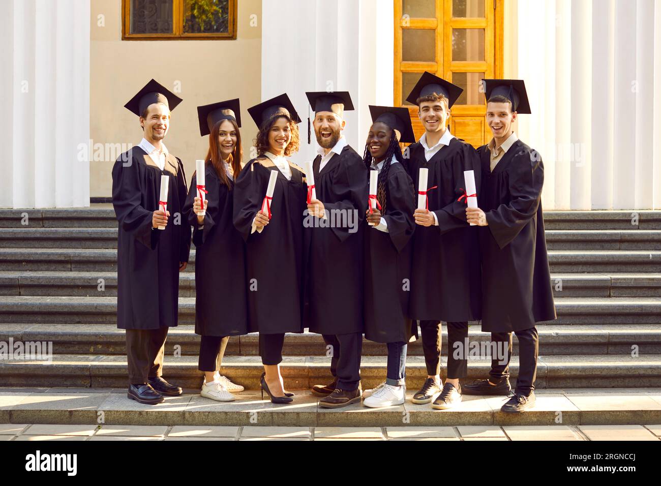 Group of happy diverse graduates with diplomas outside of their college ...