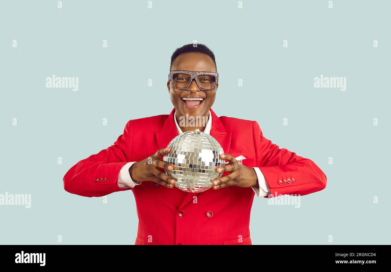 Cheerful energetic dark-skinned man holding disco ball is preparing for ...