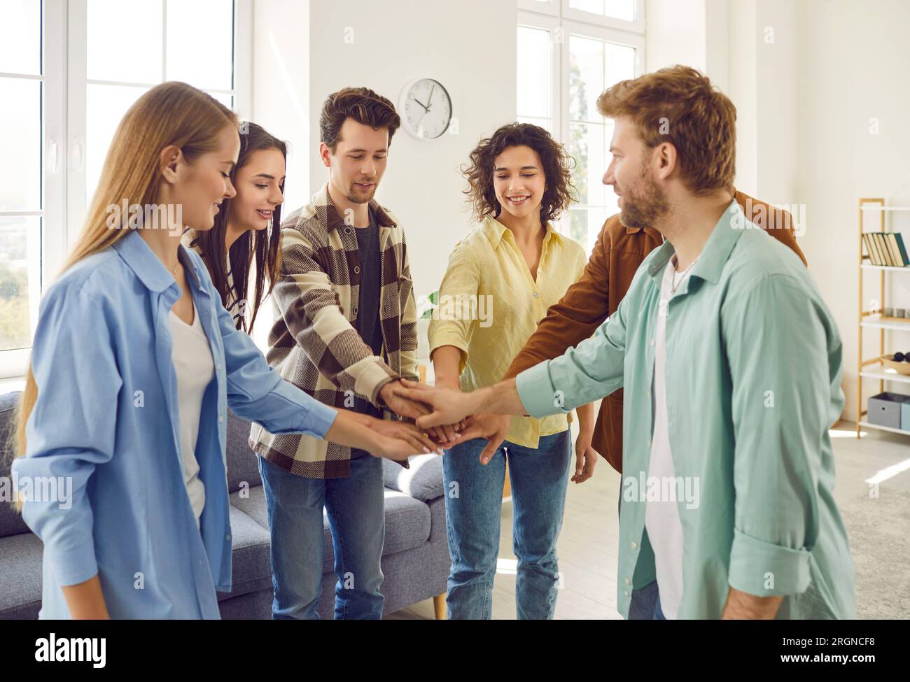 Happy smiling people friends putting their arms together in a stack ...
