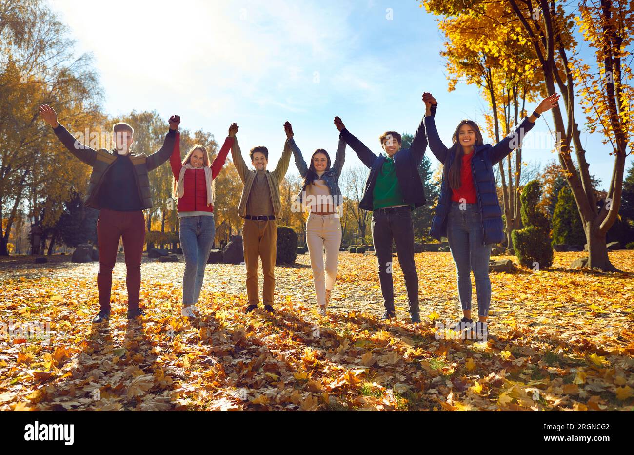 Happy friends standing together raising their hands in park Stock Photo ...