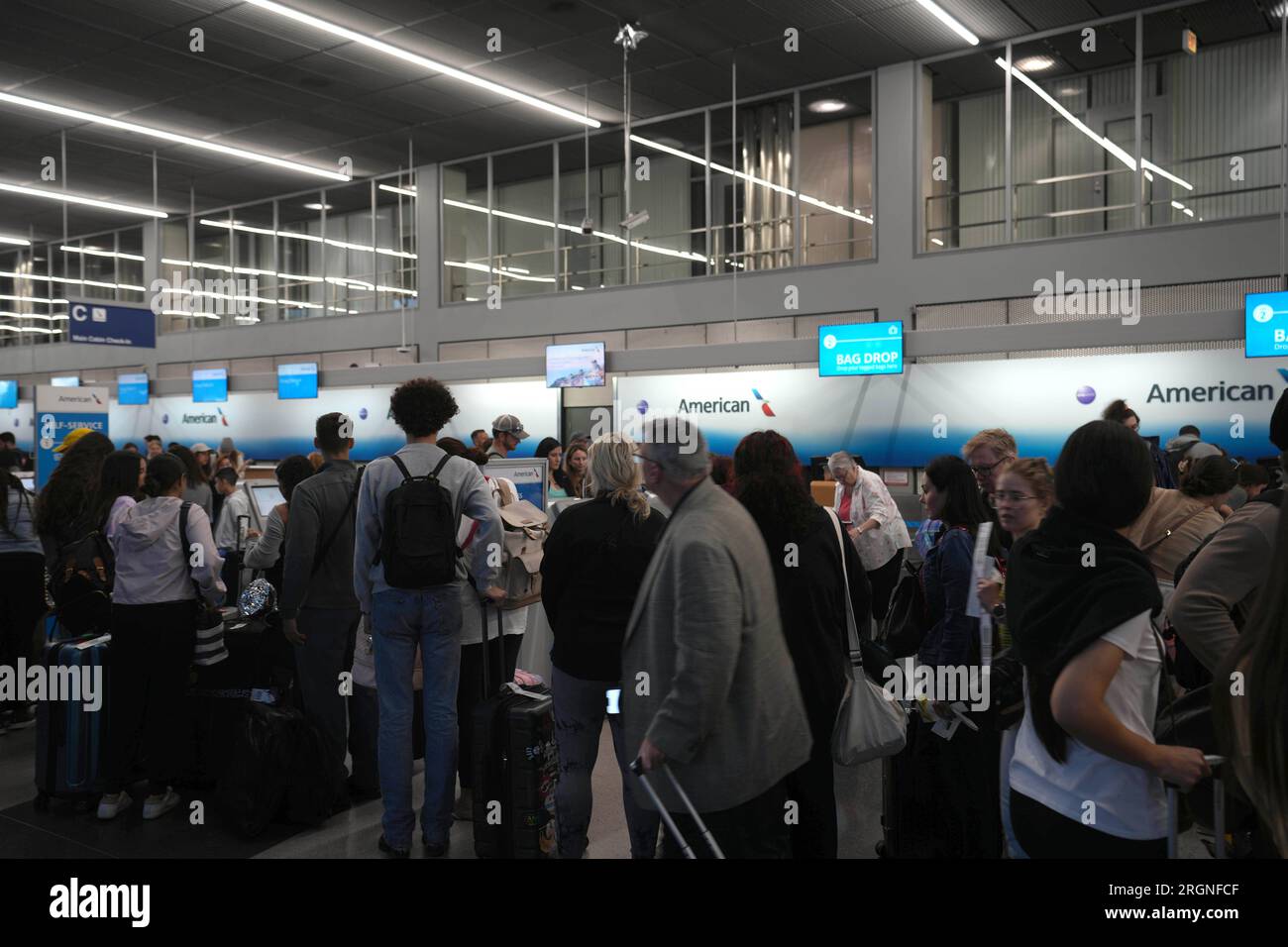 Passengers stand in line to check in luggage at an American Airlines ...