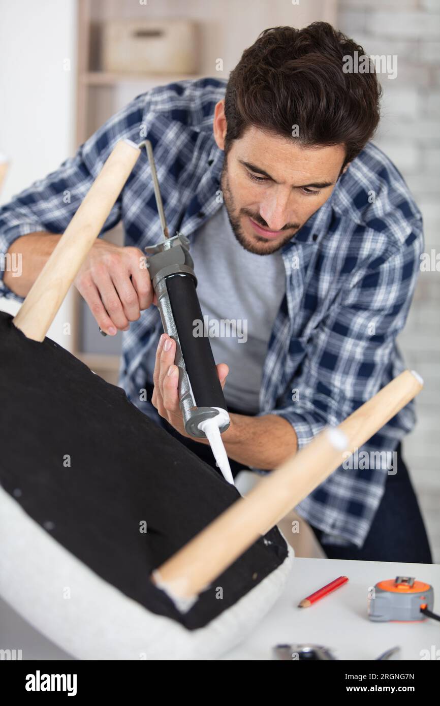 man using sealant gun to repair broken chair Stock Photo - Alamy