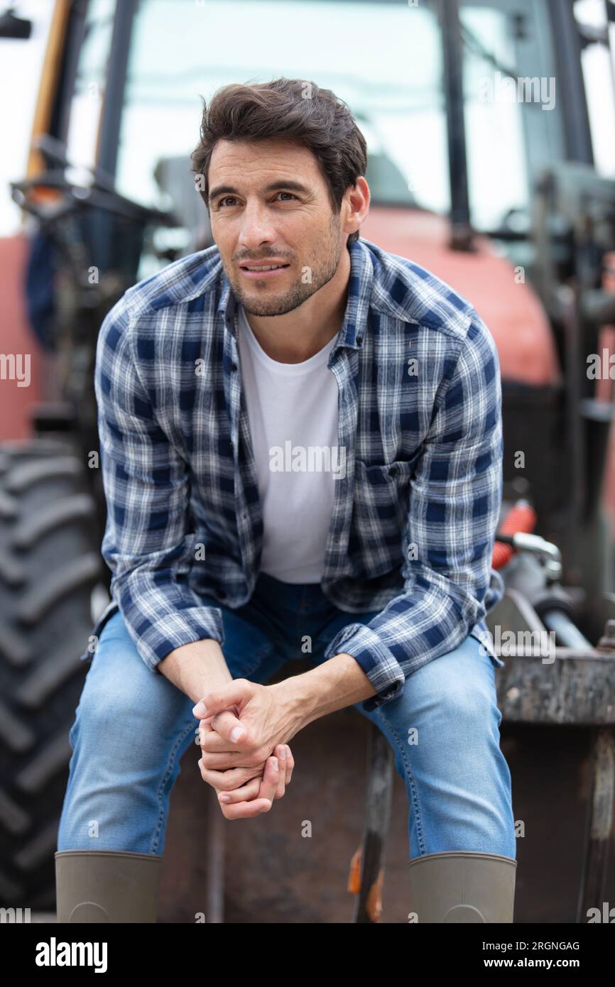 handsome young farmer sitting on his tractor Stock Photo - Alamy