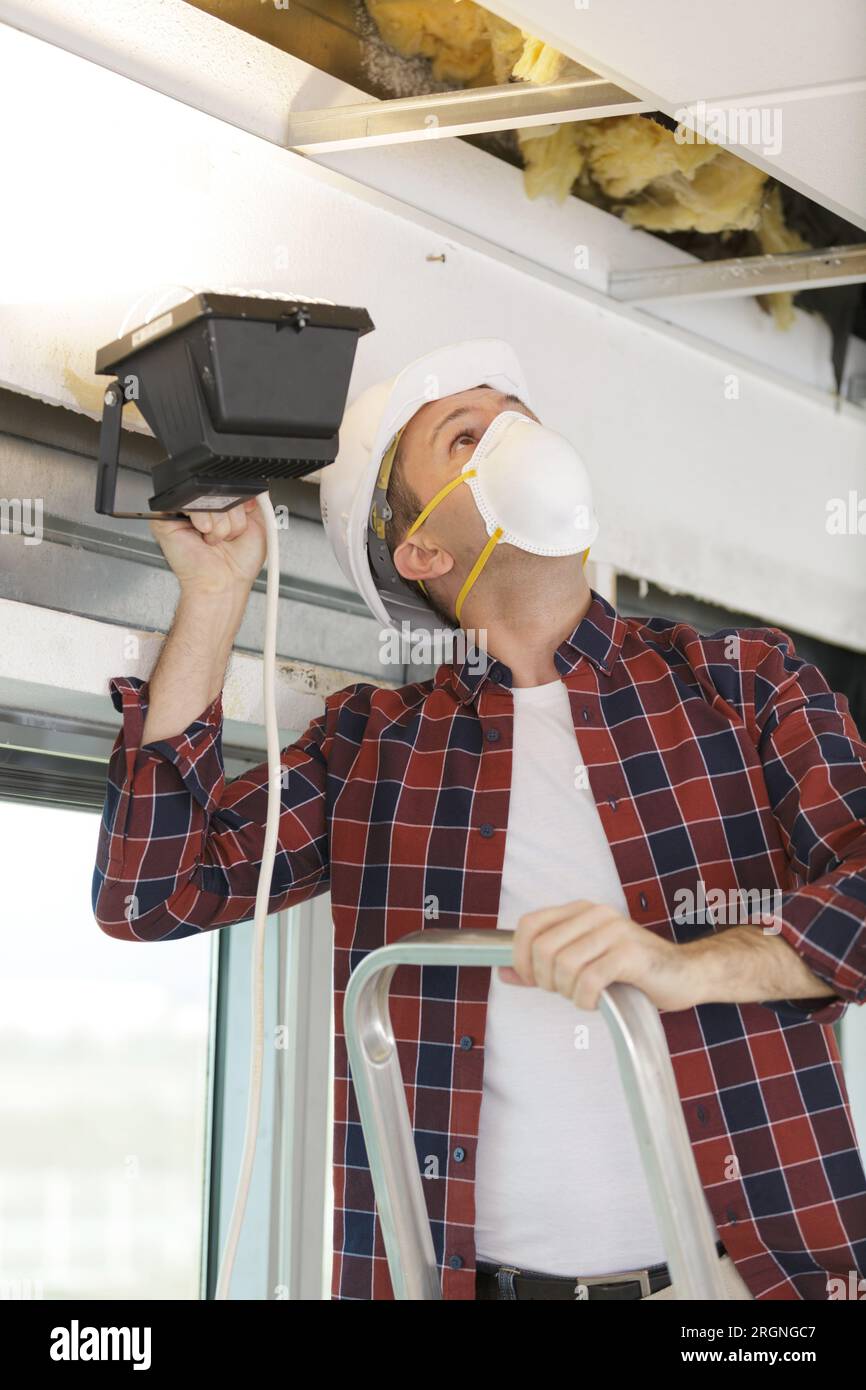 electrician is checking ceiling with a light Stock Photo - Alamy