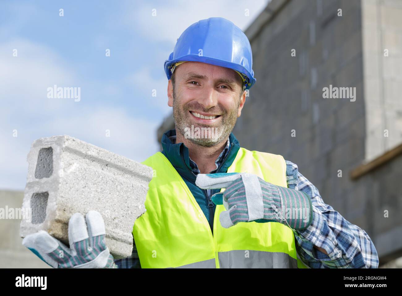 happy male builder point at cement block Stock Photo - Alamy