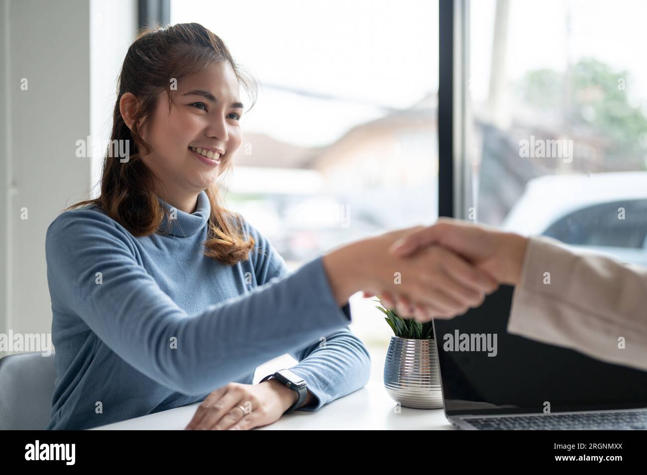A beautiful Asian female client shakes hands with a businesswoman after ...