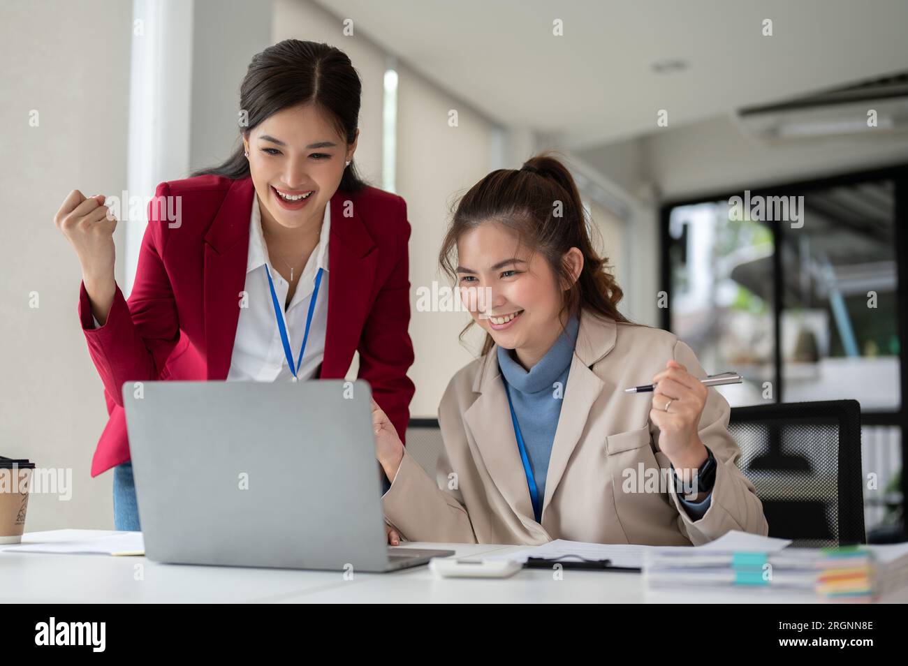 Two cheerful and excited Asian businesswomen are celebrating their ...