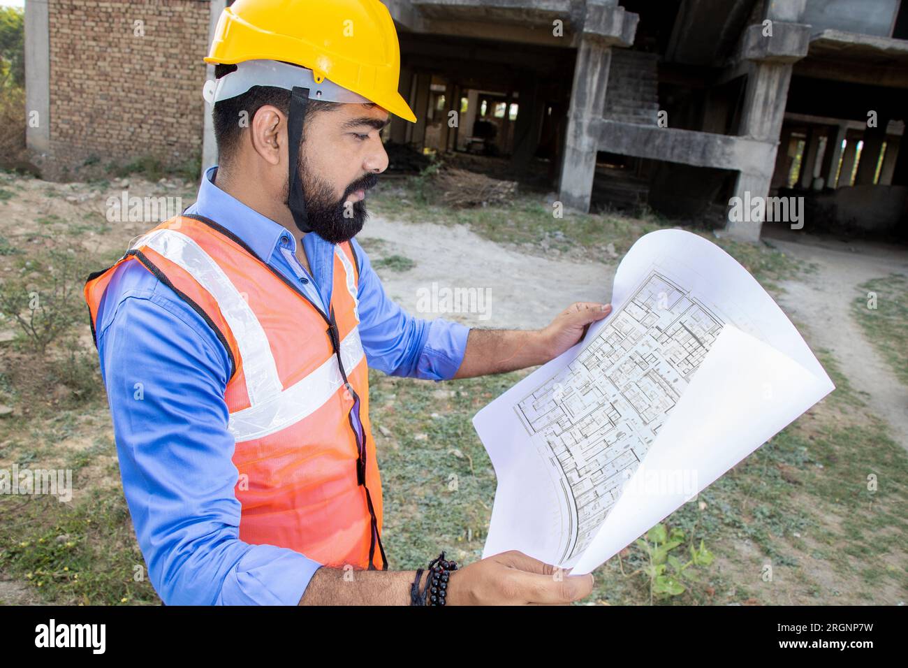 Young Indian male civil engineer or architect wearing helmet and vest ...