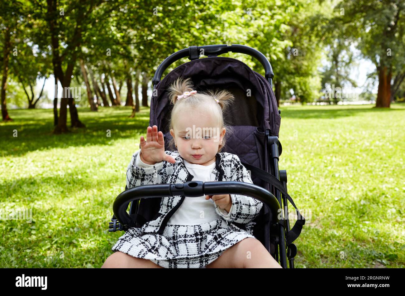 Baby in stroller on a walk in summer park. Adorable little girl sitting ...