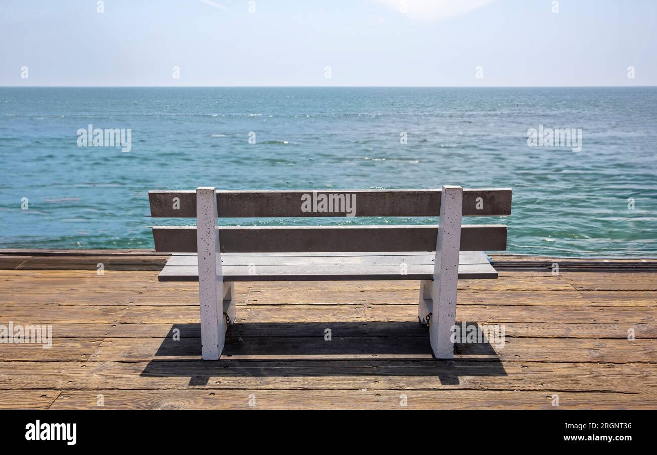Empty wooden park bench on waterfront wood platform. Sunny day, calm ...