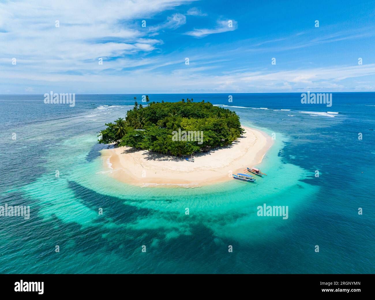 San Victor Island with white sand beach under blue skies and clouds ...